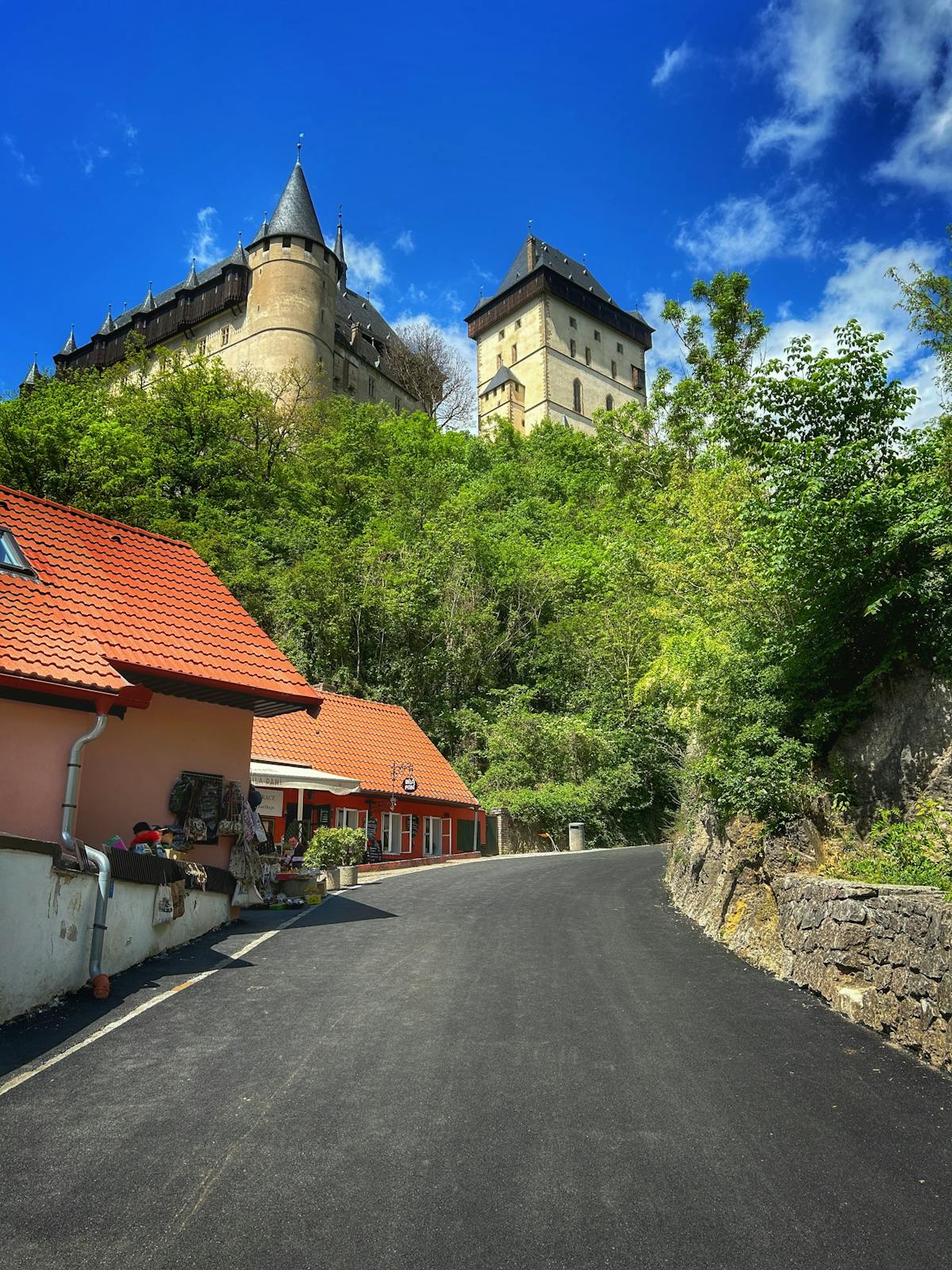 Karlstejn Castle surrounded by lush greenery under a clear blue sky