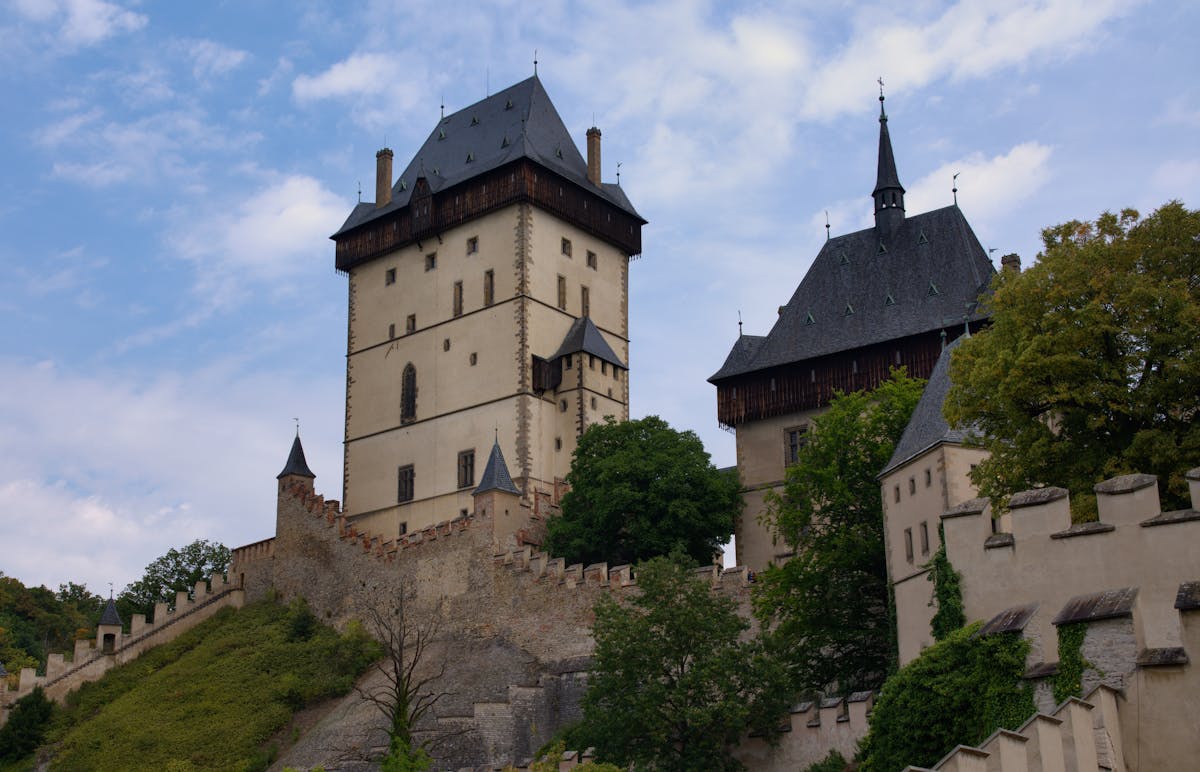 Medieval Karlstejn Castle surrounded by lush green forest on a hill