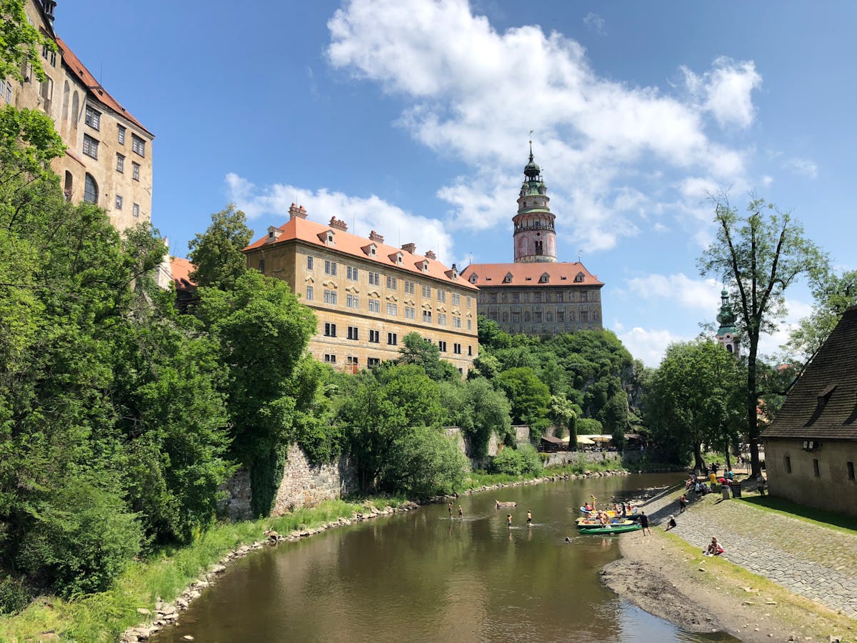 Cesky Krumlov Castle surrounded by green trees with the Vltava River flowing below