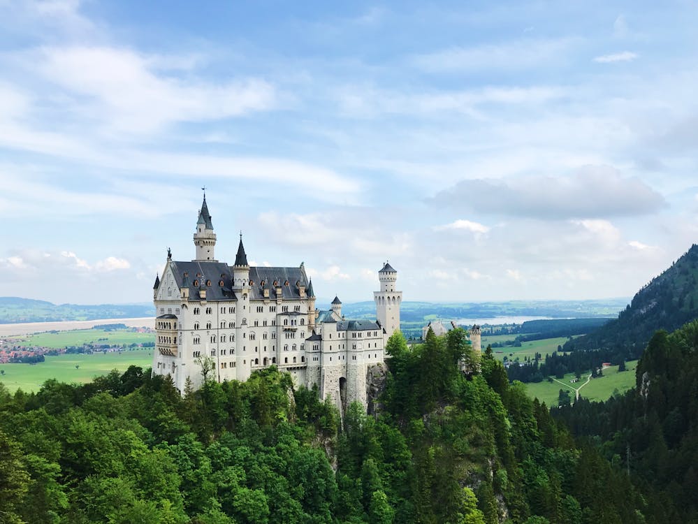 White towers of Neuschwanstein Castle rising through surrounding trees