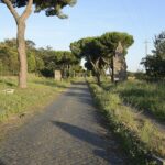 The Appian Way near Rome showing original Roman stone pavement lined with trees and ancient tombs