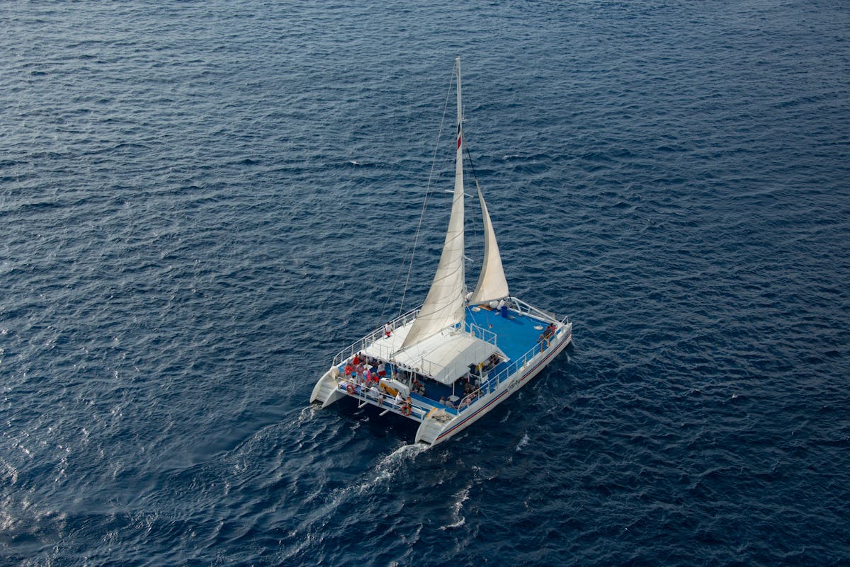 Aerial shot of a catamaran full of passengers sailing on clear blue sea