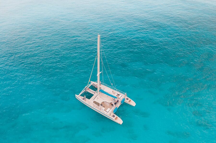 Aerial view of catamaran sailing in crystal clear turquoise waters