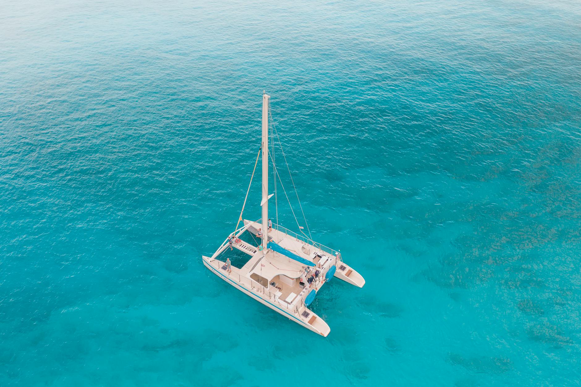 Aerial view of catamaran sailing in crystal clear turquoise waters