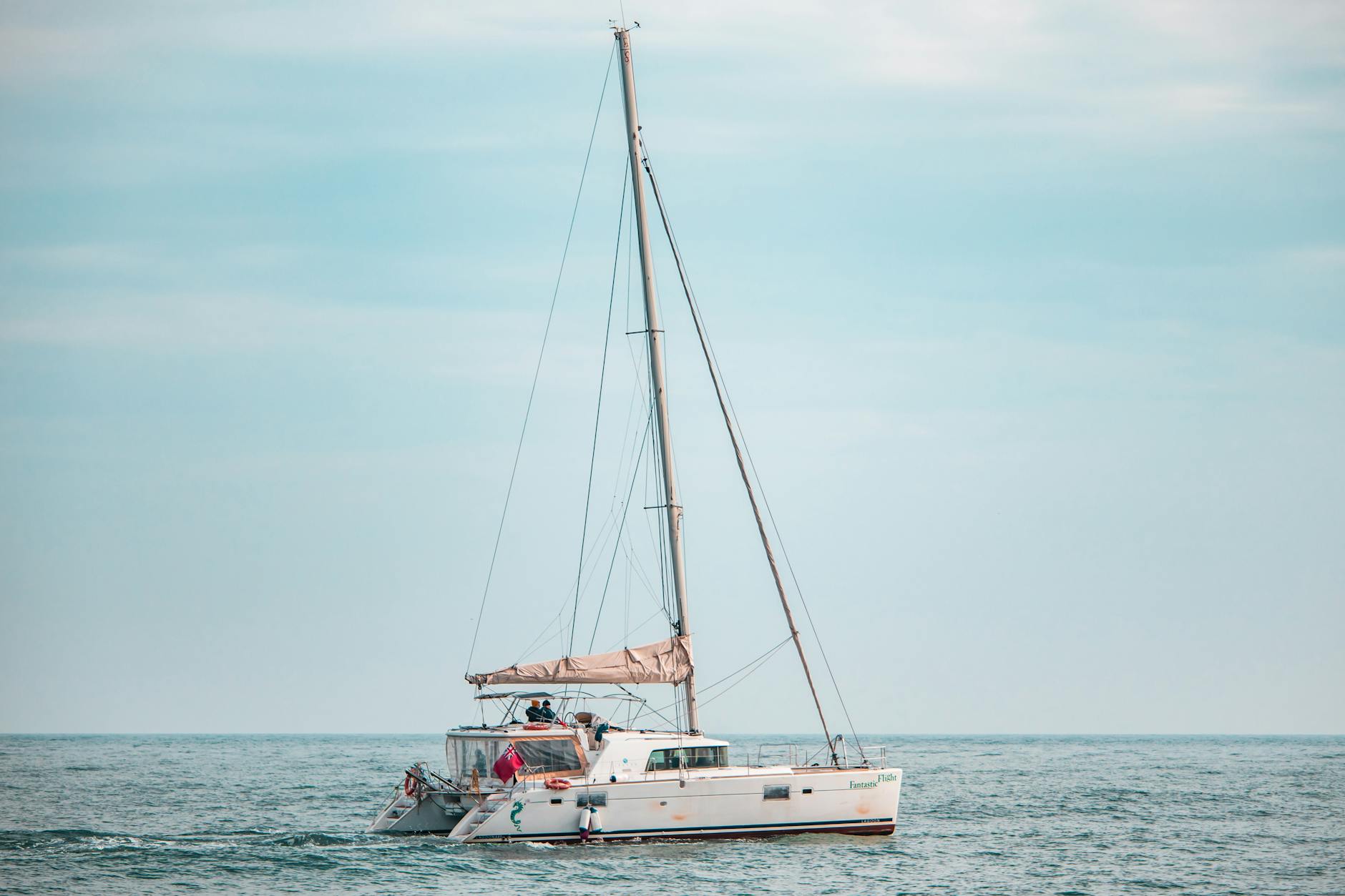Catamaran sailing peacefully on calm sea under pastel sky at sunset