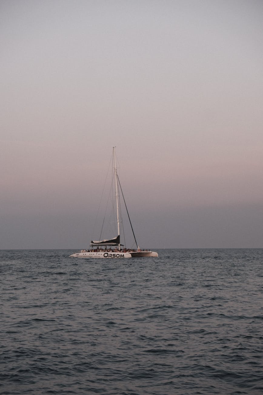 Catamaran sailing at sunset on calm ocean waters