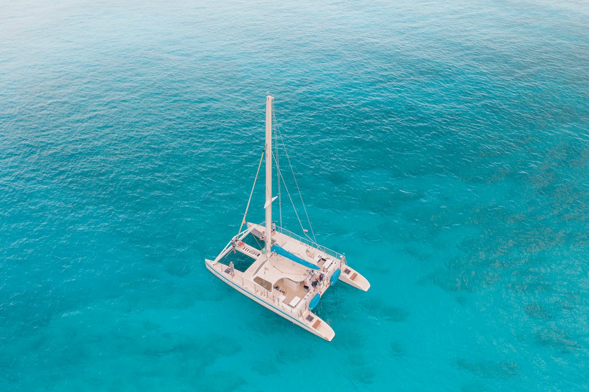 Aerial view of a catamaran sailing in crystal clear turquoise waters
