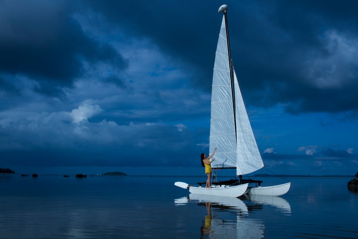 Woman sailing a catamaran on calm ocean waters during twilight