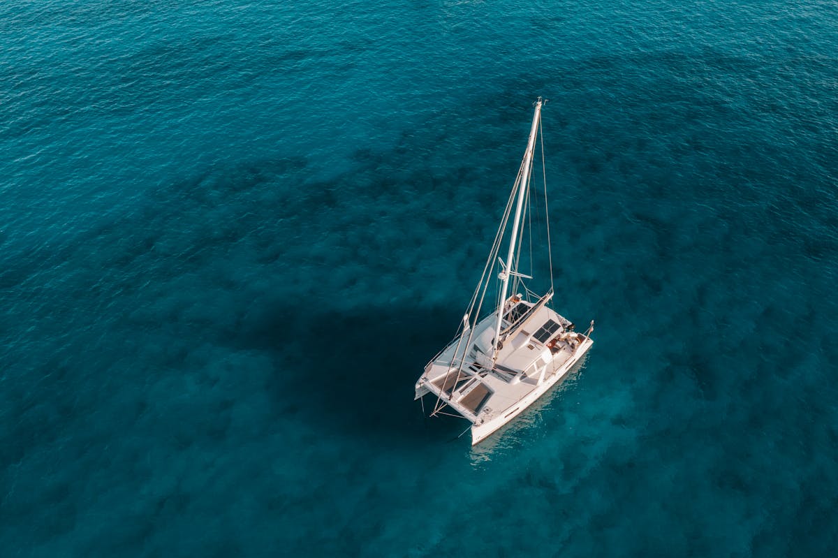 Aerial view of a catamaran sailing on crystal clear blue water