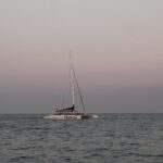 Catamaran sailing on calm Mediterranean waters at sunset