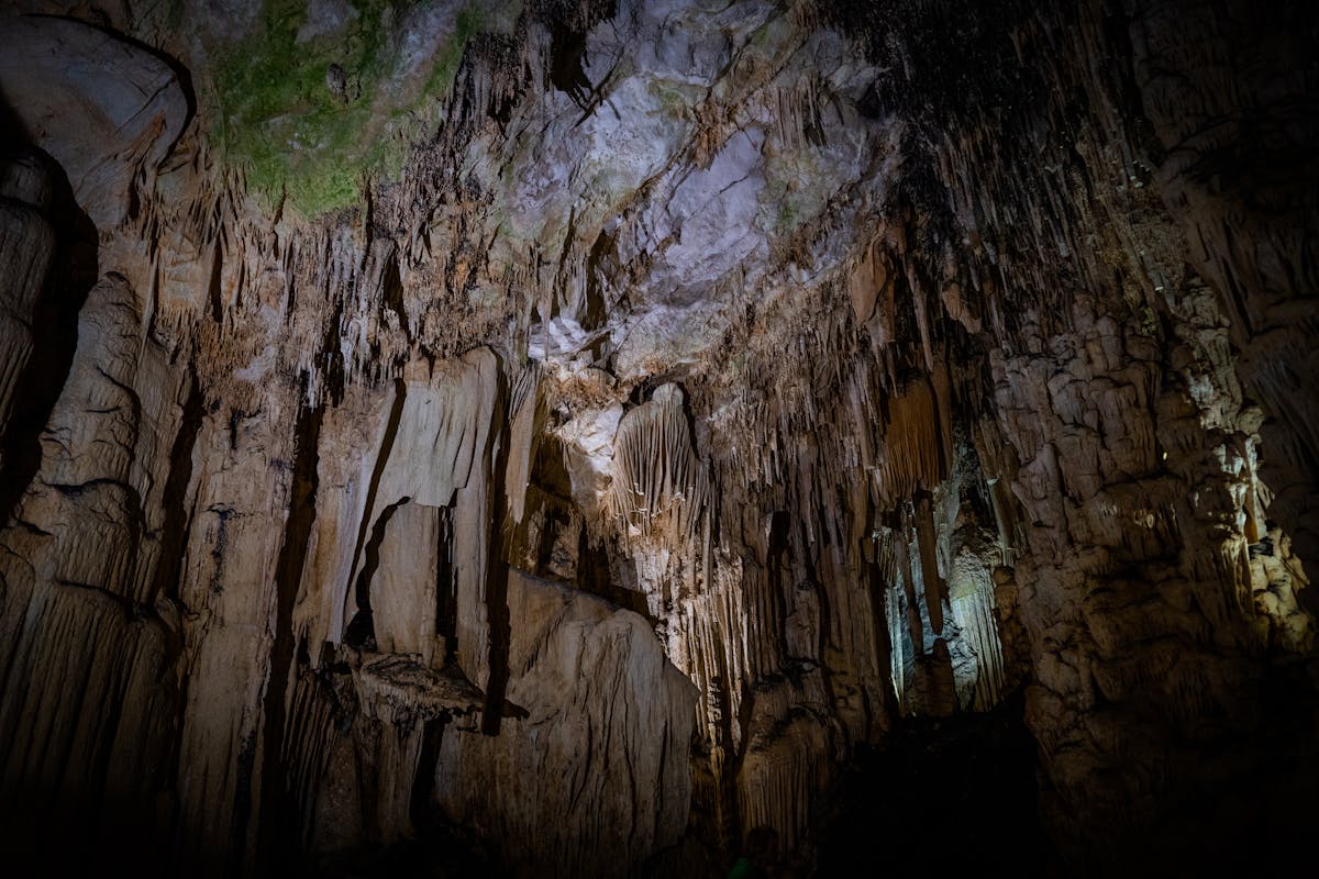 Dimly lit cave interior with stalactite and stalagmite formations