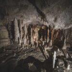 Stalactites and stalagmites formations inside an underground cave with dim lighting