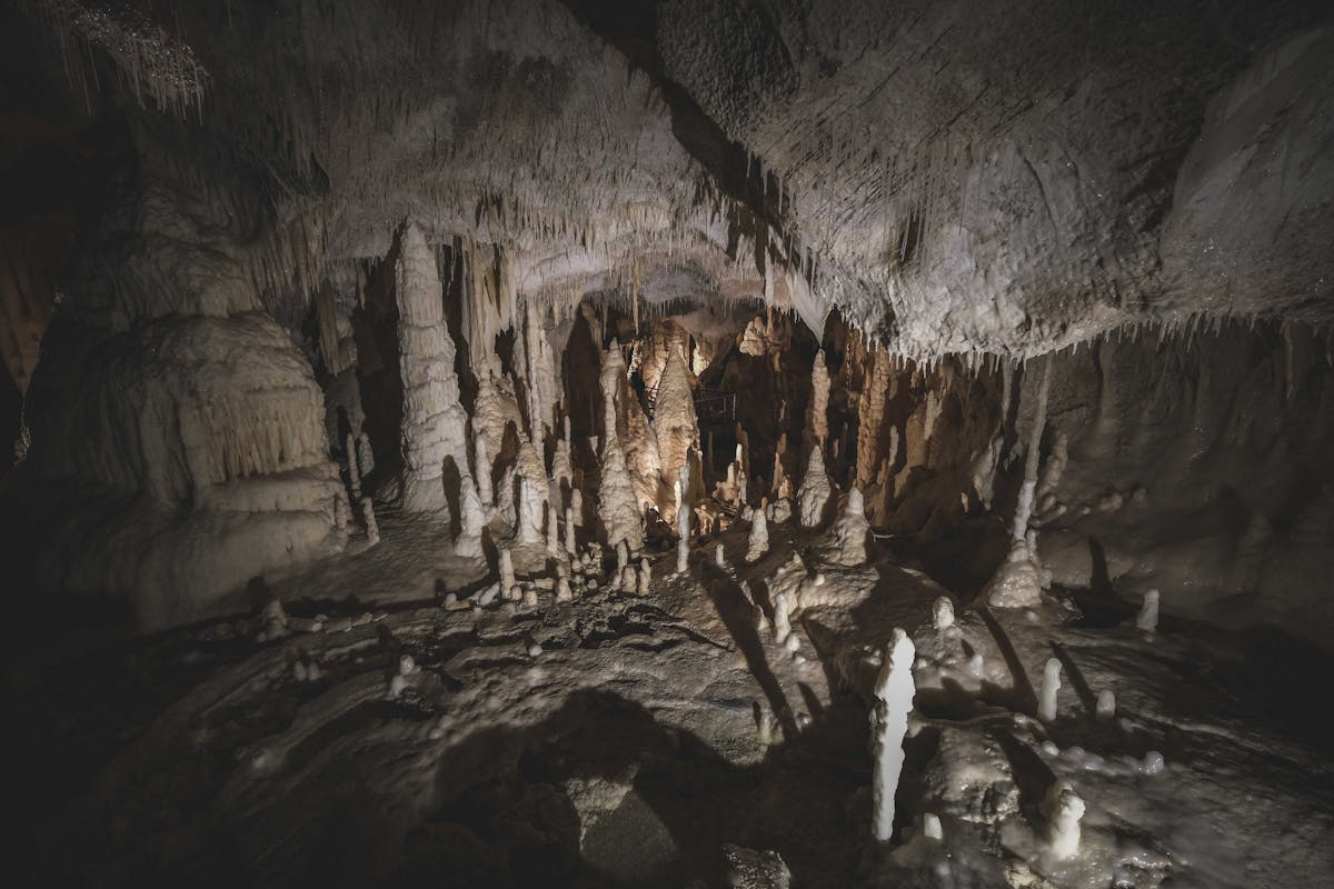 Stalactites and stalagmites formations inside an underground cave with dim lighting