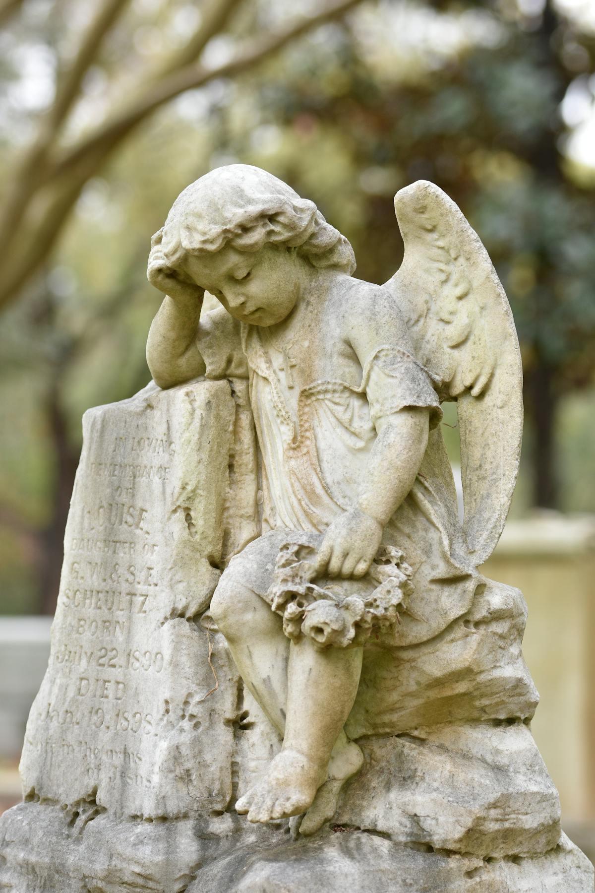 Beautiful stone angel statue in a tranquil cemetery surrounded by trees