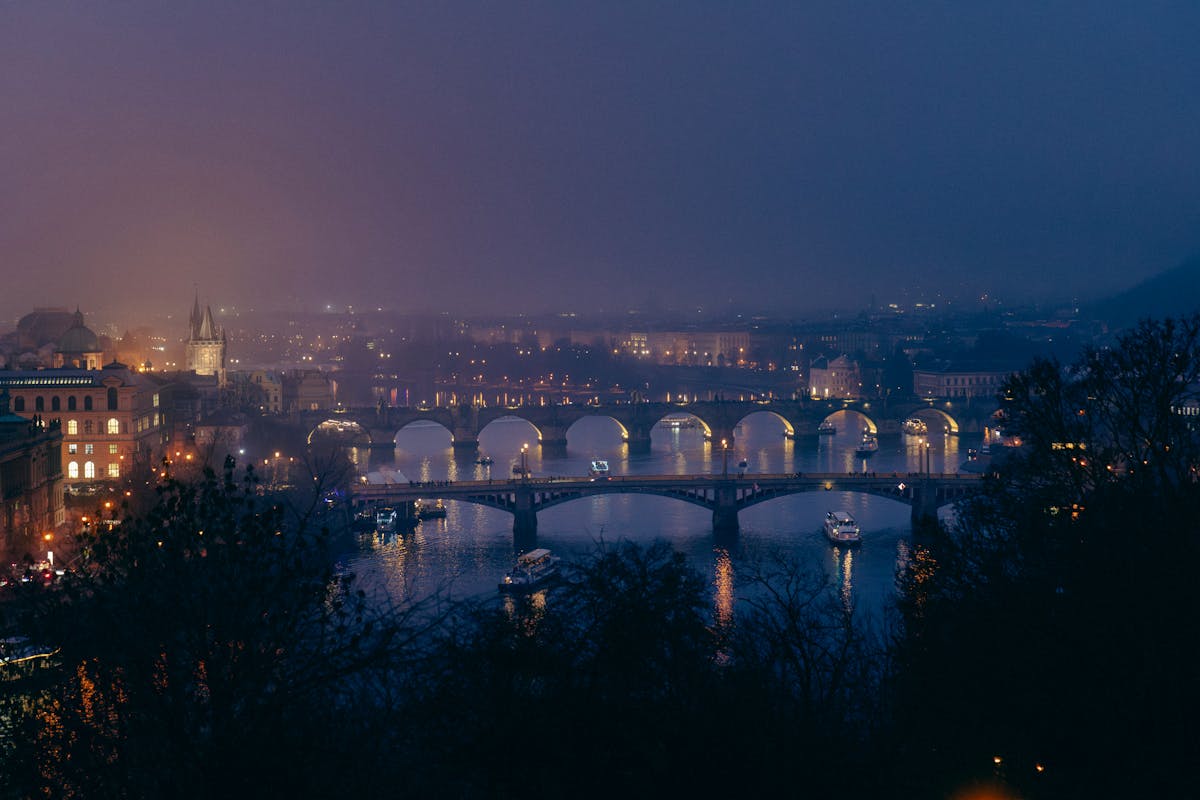 Charles Bridge illuminated at night in Prague with misty atmosphere