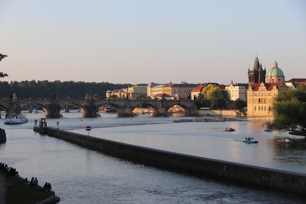 Sunset behind Charles Bridge casting golden light across the Vltava River in Prague