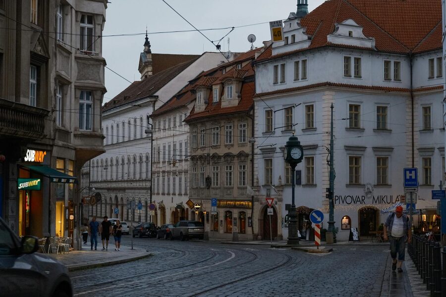 Historic Prague street with colorful building facades and cobblestone road at dusk