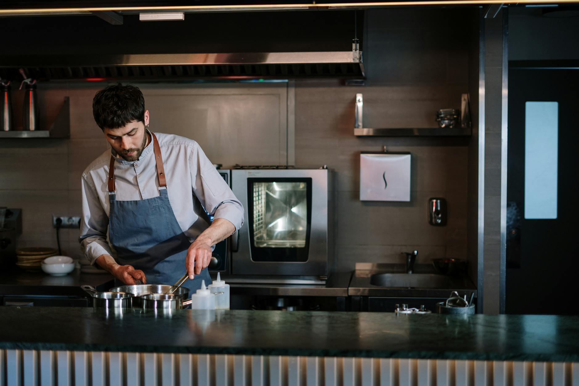 Chef in a blue apron cooking at a modern open kitchen counter