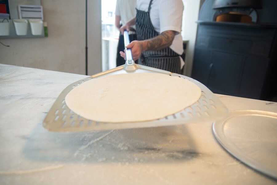 A chef skillfully handling pizza dough in a professional kitchen setting