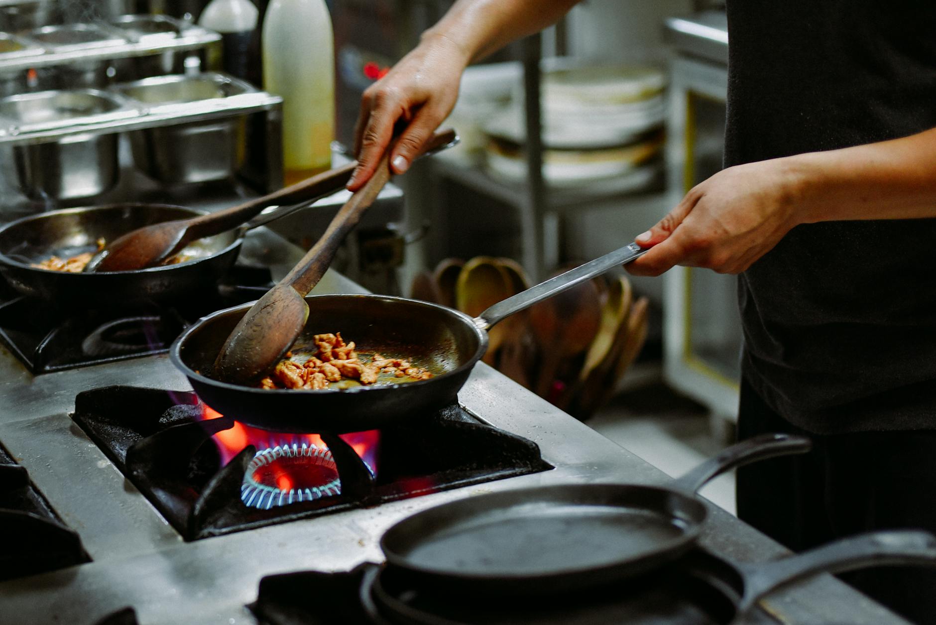 Chef preparing a dish with sauteed ingredients in a restaurant kitchen