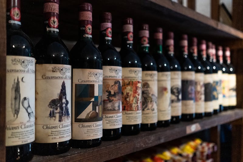 Chianti Classico red wine bottles neatly lined up on a wooden cellar shelf in Tuscany