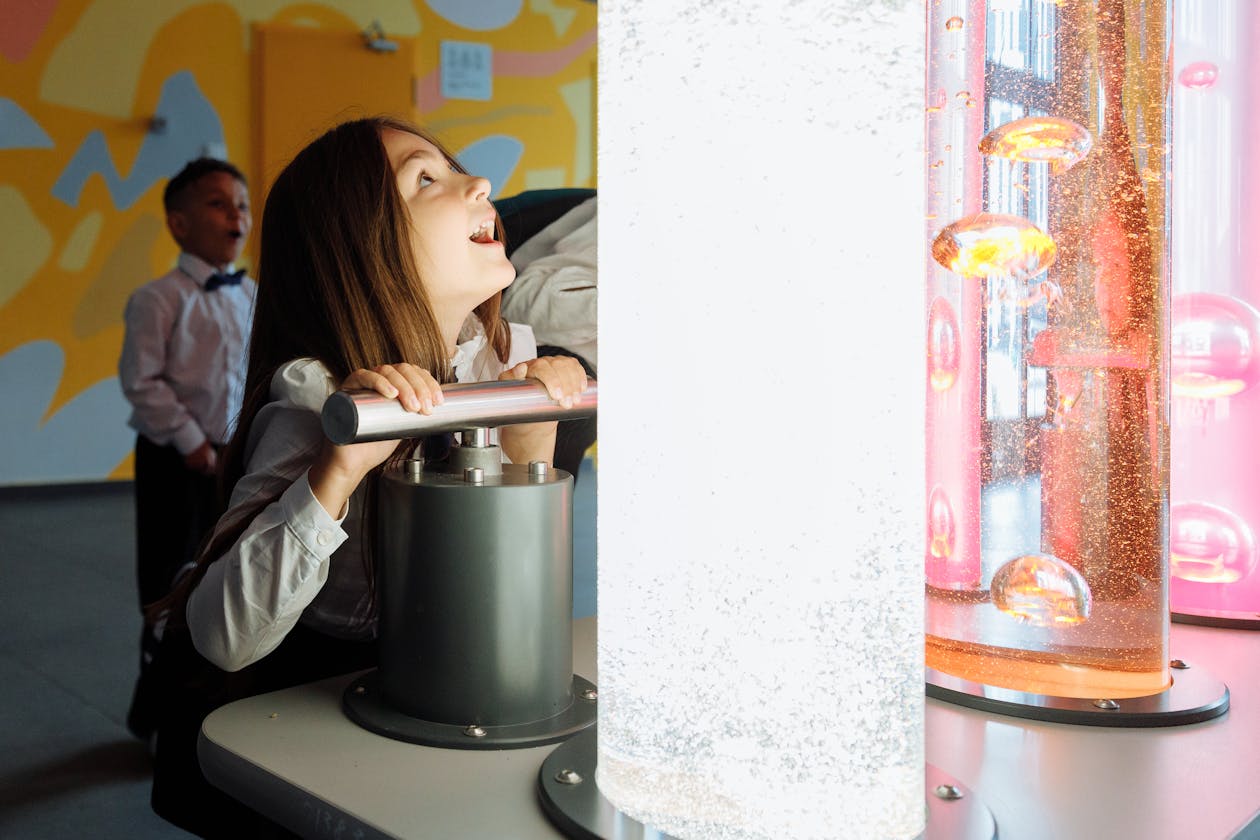 Children engaging with a colourful interactive science exhibit with lights and liquids
