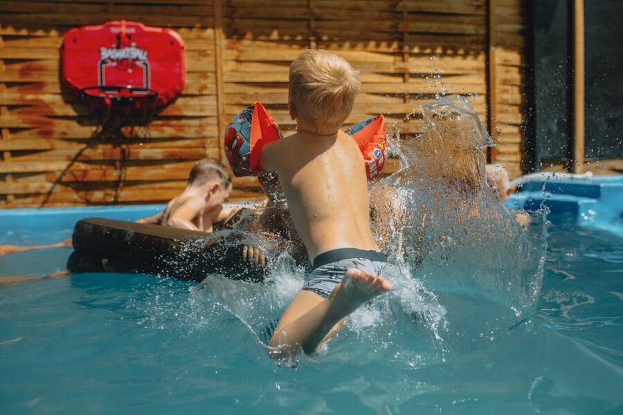 Children having fun splashing in an outdoor swimming pool during a summer day