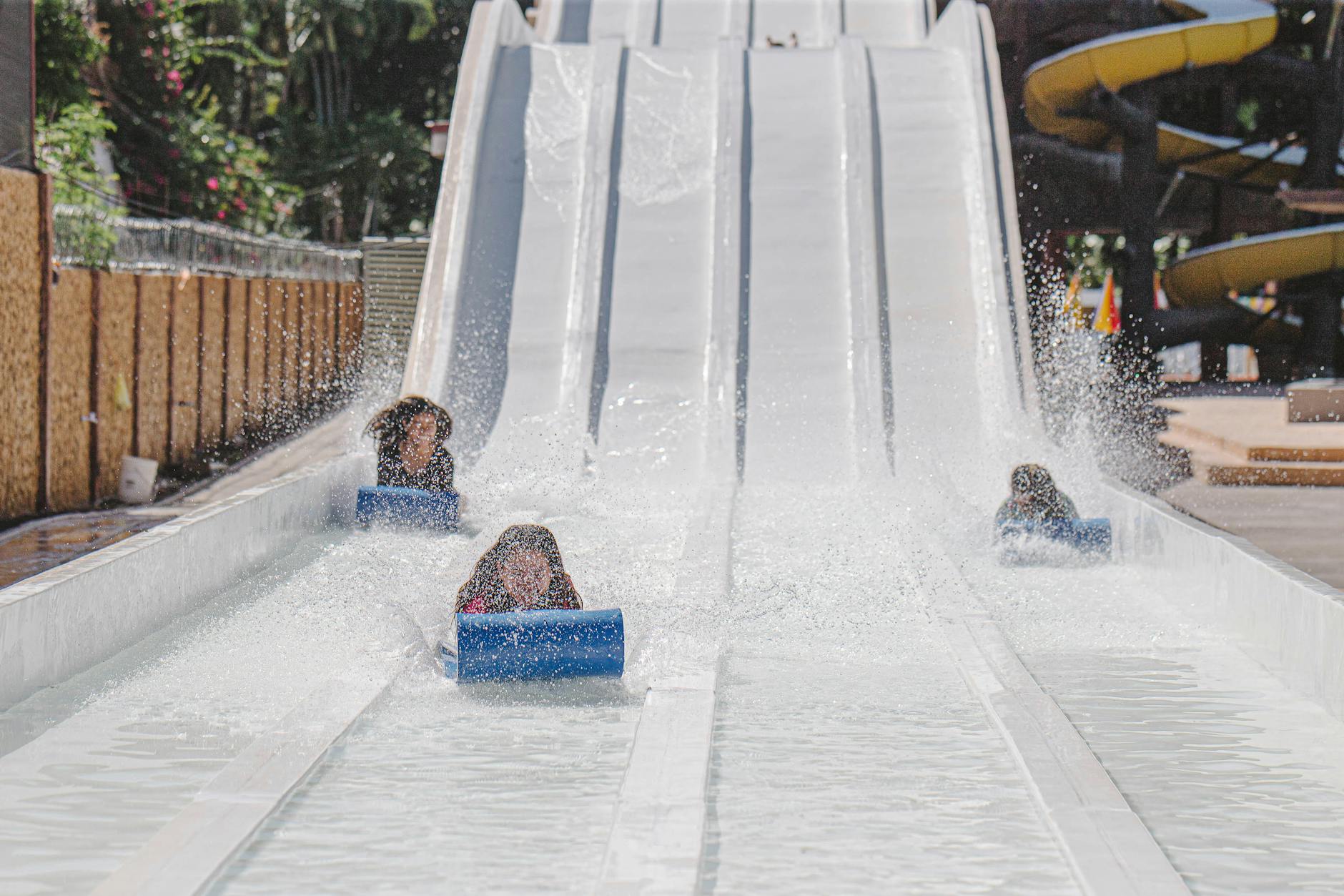 Children having fun on a water slide at a park on a sunny day