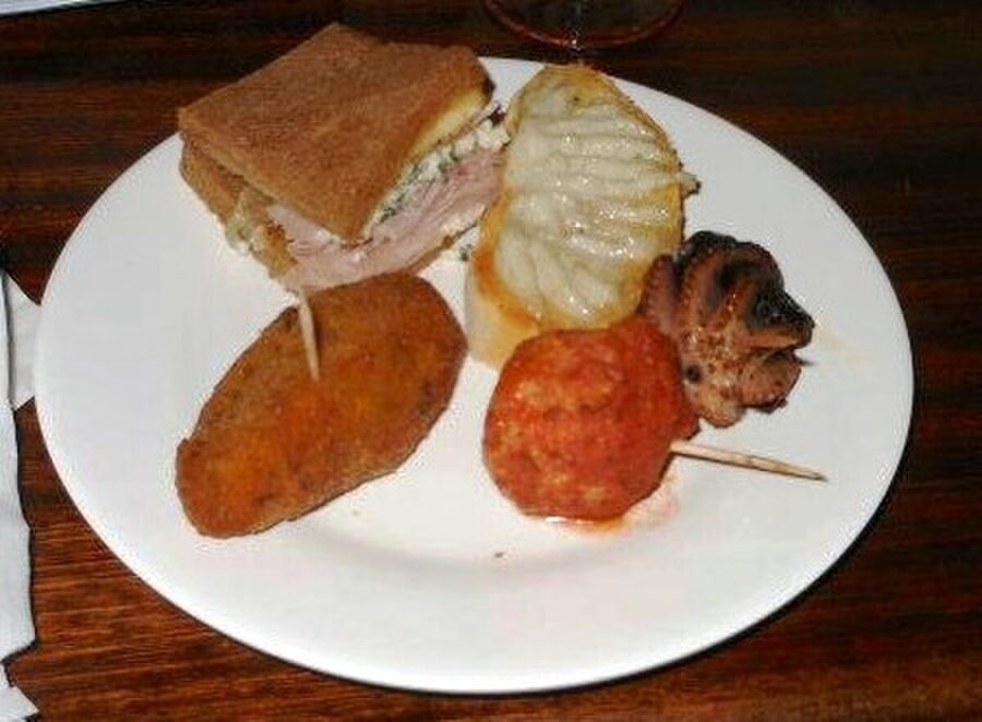 Various cicchetti appetizers displayed under glass at a Venice wine bar counter