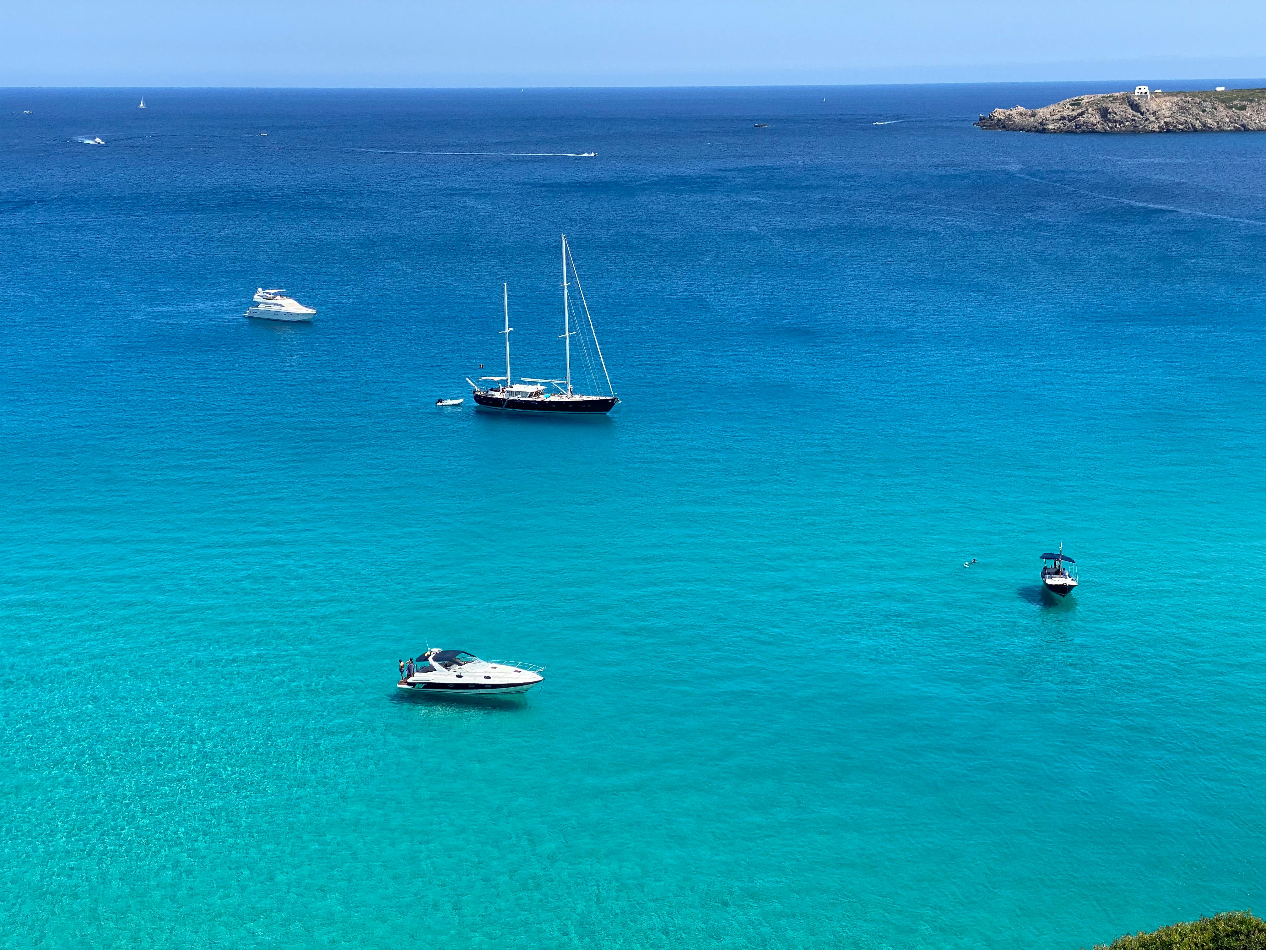 Sailboats on turquoise waters at Ciutadella harbour in Menorca