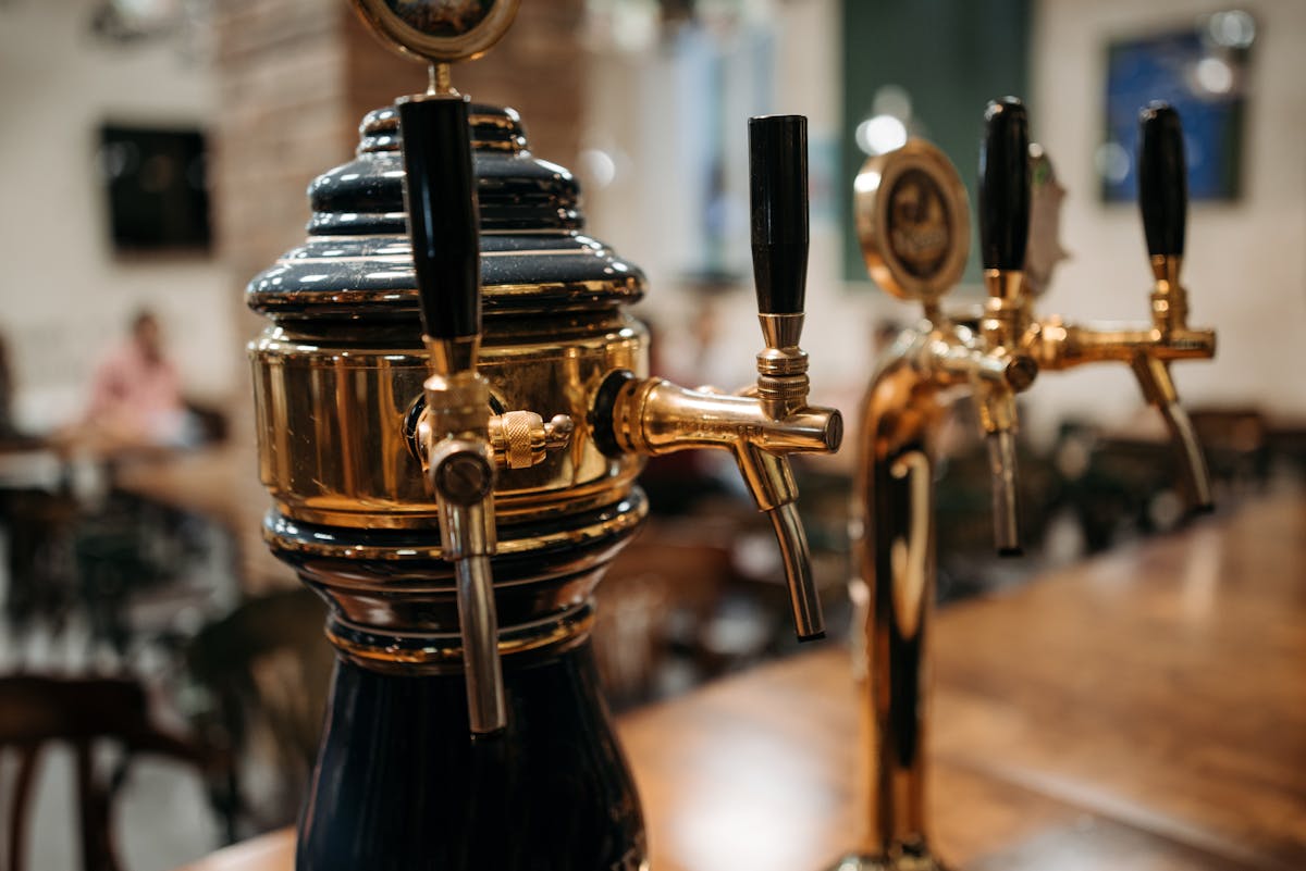 Detailed view of classic beer taps at a bar showcasing polished metal and wood textures