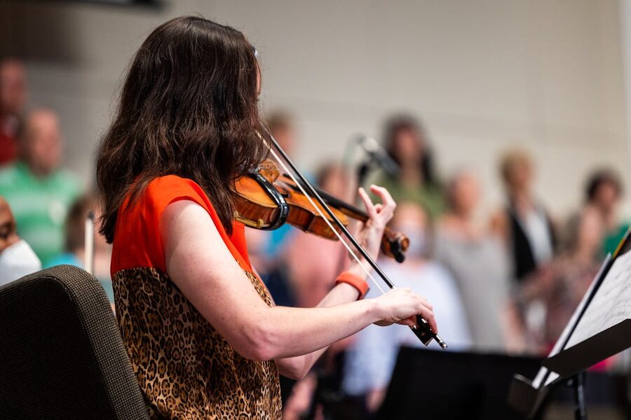 A violinist playing during an indoor classical concert with an audience watching
