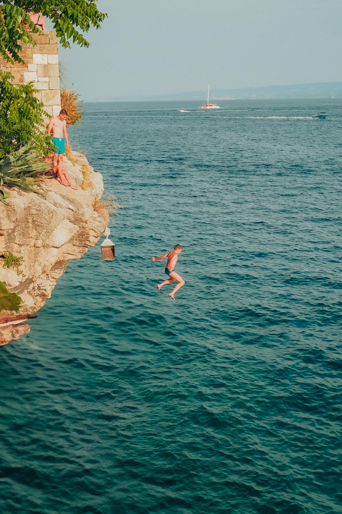 Cliff diver leaping into crystal clear ocean water