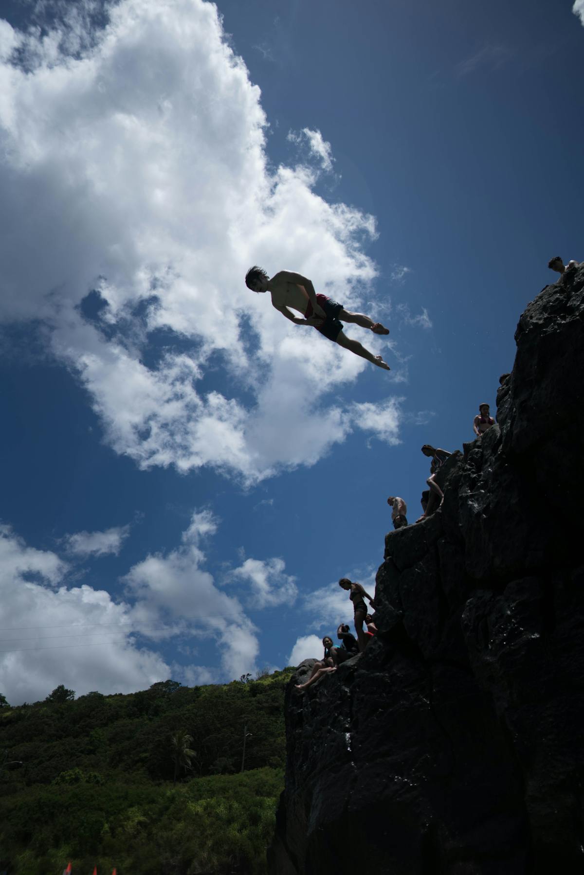 Person cliff diving into the ocean on a sunny day