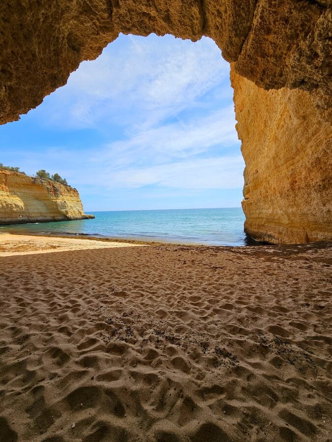 View from a cave tunnel leading to a pristine Algarve beach in Portugal