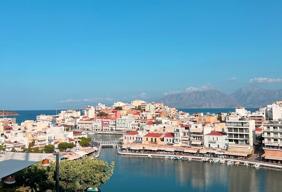 Colorful coastal city of Agios Nikolaos with mountain backdrop, ideal for travel inspiration.