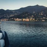 A boat on Lake Como at sunrise with a mountain village in the background