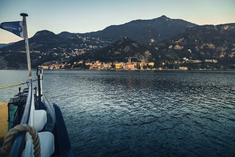 A boat on Lake Como at sunrise with a mountain village in the background