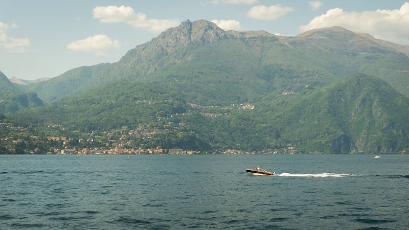 Motorboat cruising on Lake Como with mountains in the background