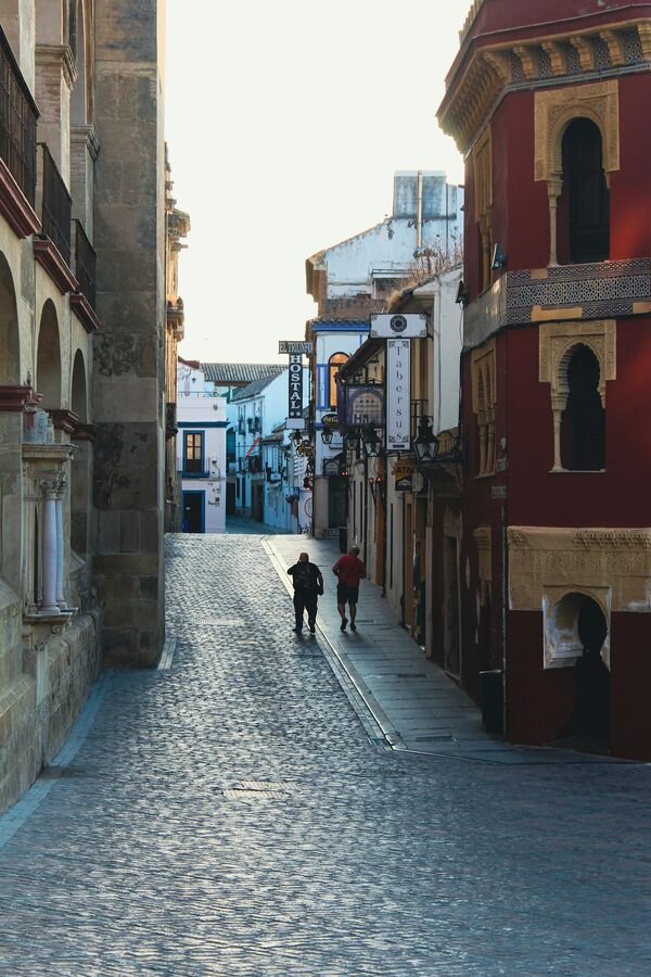 People strolling along a cobblestone street lined with historic buildings in Cordoba
