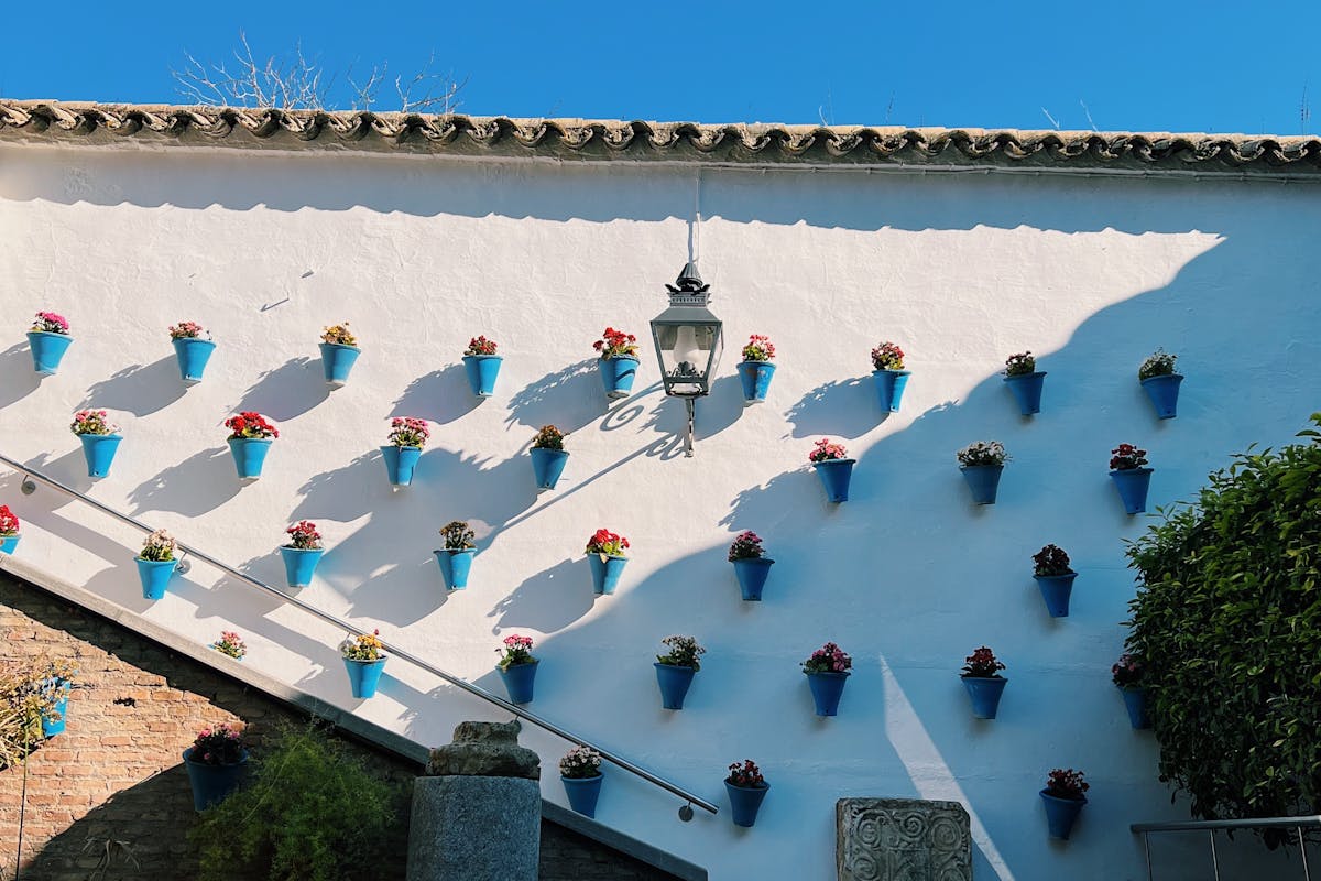 Ceramic flower pots on a whitewashed wall under blue sky in Cordoba