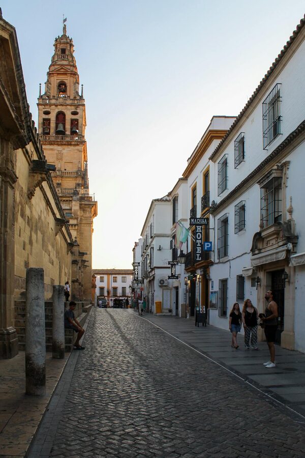 View down a historic Cordoba street with the Mosque-Cathedral bell tower in the distance