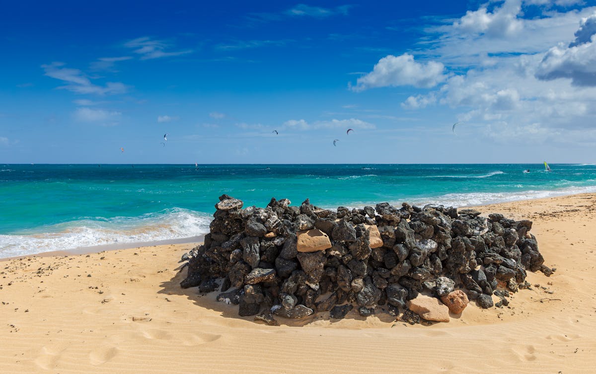 Stone structure on Corralejo Beach with turquoise waters and kite surfers