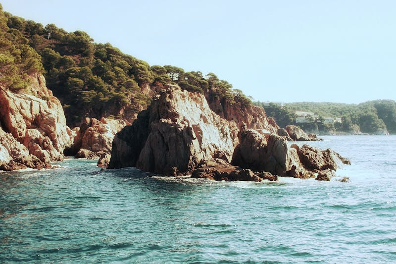 Dramatic rocky cliffs meeting turquoise sea along the Costa Brava coast in Spain