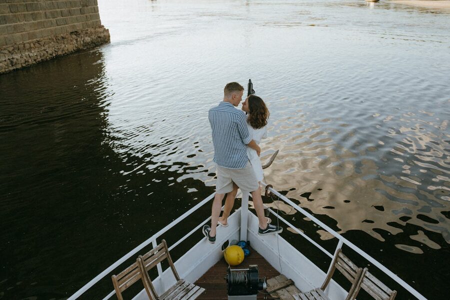Romantic couple sharing intimate moment on bow of yacht during sunset