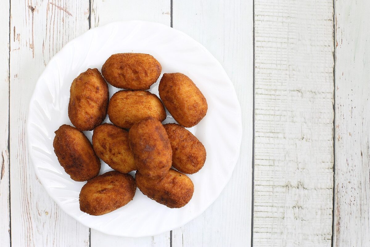 Golden fried Spanish croquetas served on a white plate with salad