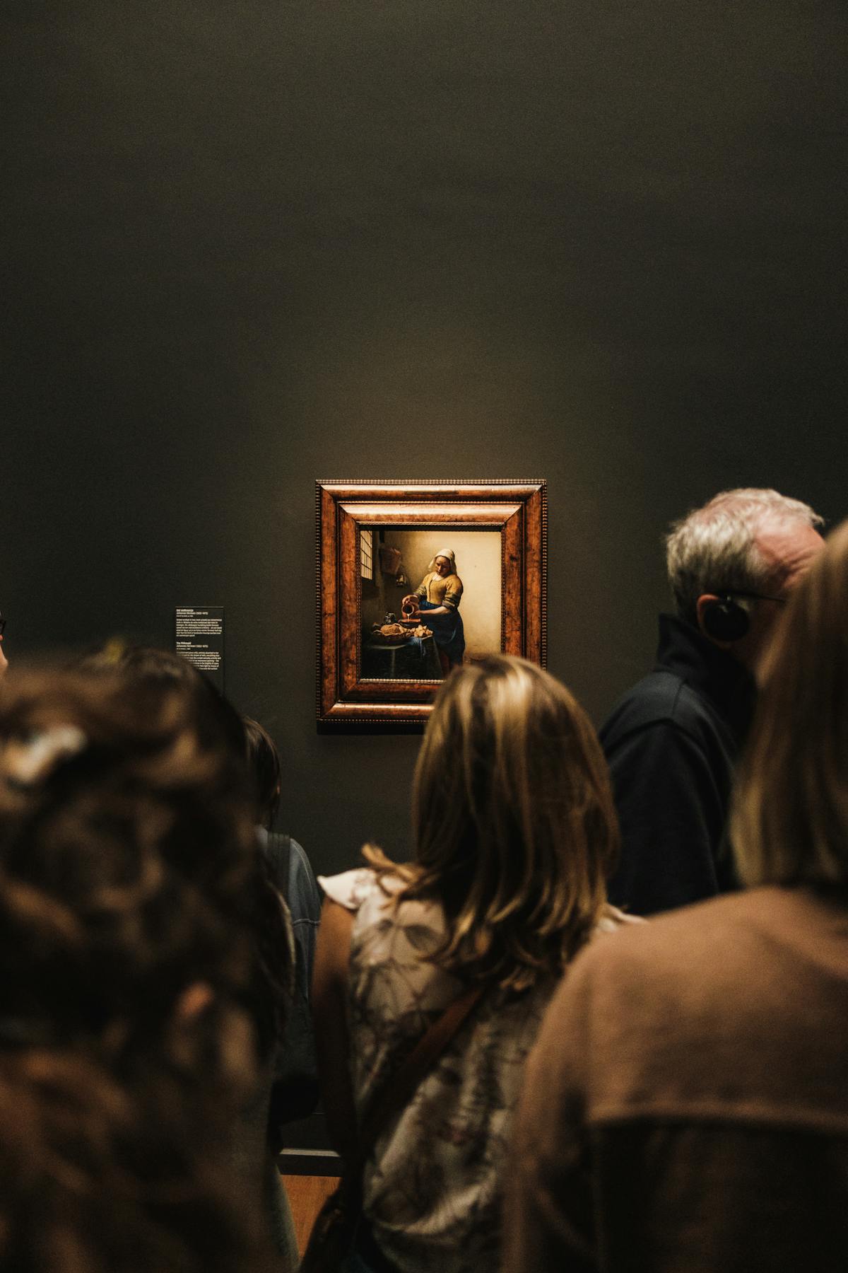 Crowd of visitors viewing a classic painting inside a museum gallery