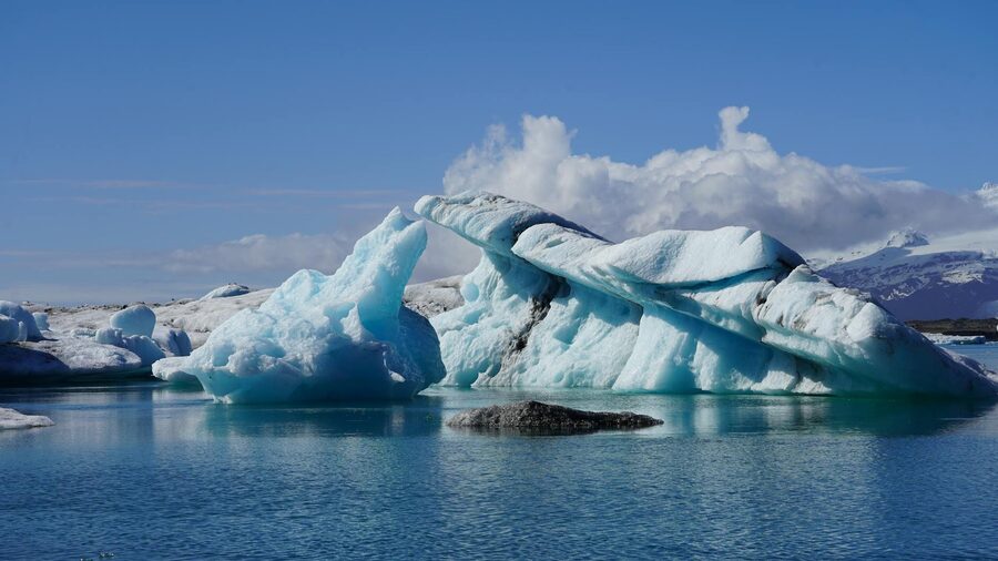 Crystal blue icebergs floating in Jokulsarlon Glacier Lagoon, Iceland, under a clear sky.