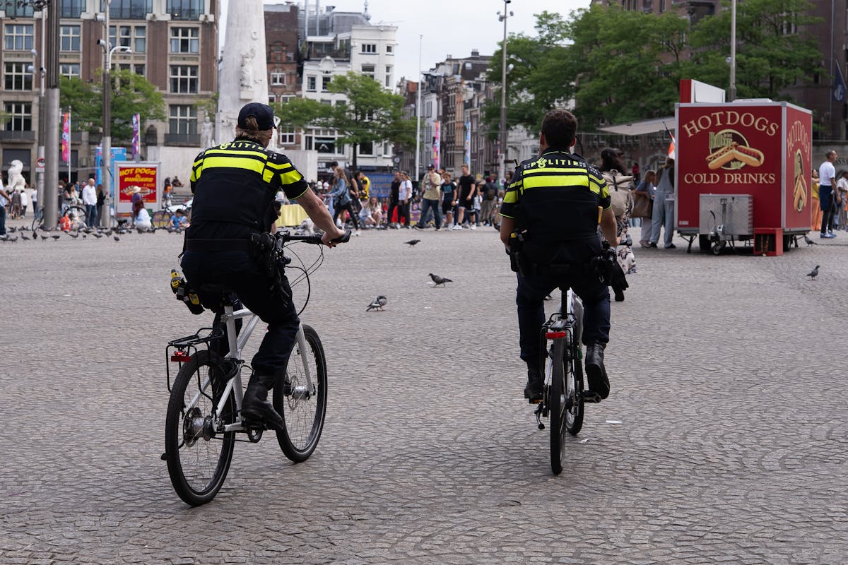 People and cyclists in Dam Square Amsterdam with surrounding buildings