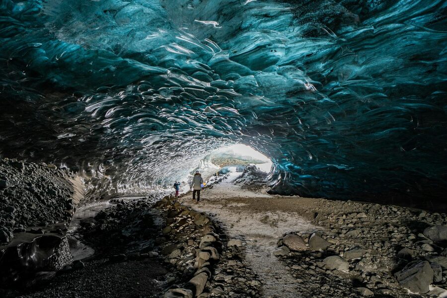 Discover the enchanting beauty of an Icelandic ice cave with travelers exploring the icy blue formati